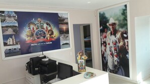 Quarto com um pôster grande de parque temático, televisão e escrivaninha com um computador e uma pequena estatueta.