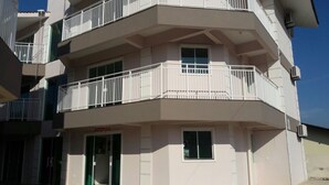 Um edifício de vários andares com varandas, entrada visível e uma placa com a inscrição 'RECEPTION'.
