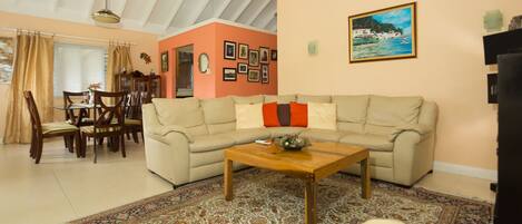 Uma sala de estar com um sofá bege, uma mesa de centro de madeira e um tapete estampado.