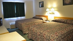 Quarto de hotel com duas camas, uma mesa e janela com cortinas.
