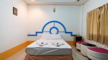 Quarto de hotel com uma cama, mesa de cabeceira, cadeira e janela com cortinas.