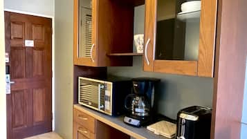 Cozinha compacta com armários de madeira, cafeteira, torradeira e micro-ondas.