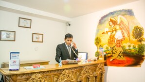 Uma receção com um homem ao telefone, diplomas emoldurados na parede e um grande quadro de um anjo.