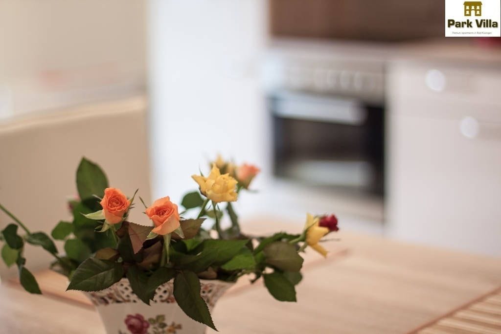 Uma mesa de jantar com um vaso de flores contendo rosas.