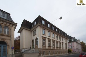 Um edifício de vários andares com estilo arquitetônico clássico, destacando uma entrada imponente com escadaria e varanda.
