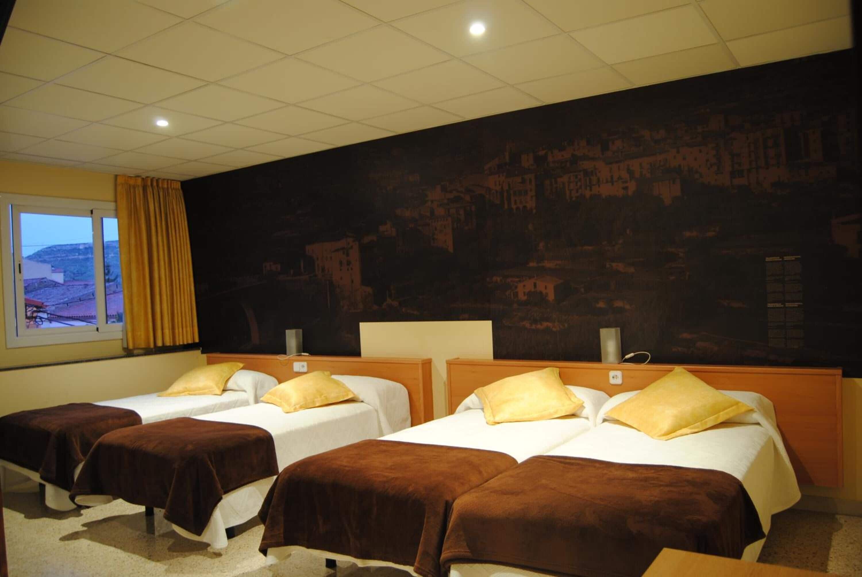 Quarto de hotel com duas camas de solteiro, uma janela grande com cortinas e um mural com vista para a cidade.