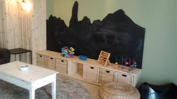 Quarto com uma mesa branca, cestos de vime, uma obra de arte preta na parede e um pufe preto.