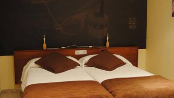 Cama de casal com roupa de cama marrom, cabeceira de madeira e um aparelho de ar condicionado acima.