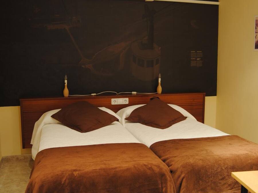 Cama de casal com roupa de cama marrom, cabeceira de madeira e um aparelho de ar condicionado acima.