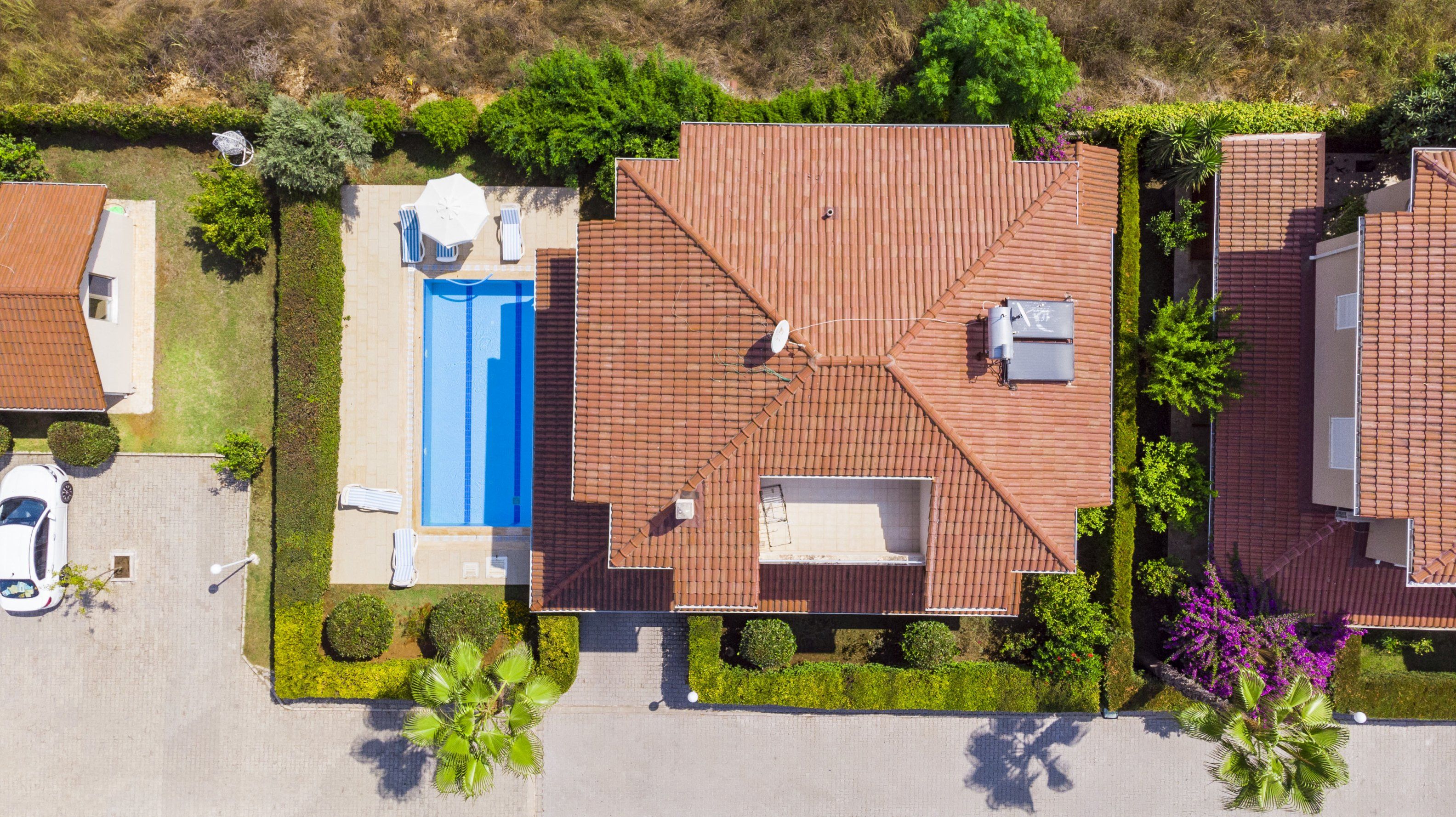 Vista aérea de uma área residencial com uma casa que tem piscina, varanda coberta e aquecedor solar de água.