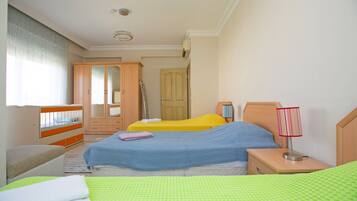 Quarto com duas camas, um guarda-roupa, uma mesa de cabeceira com abajur e uma janela com cortinas.