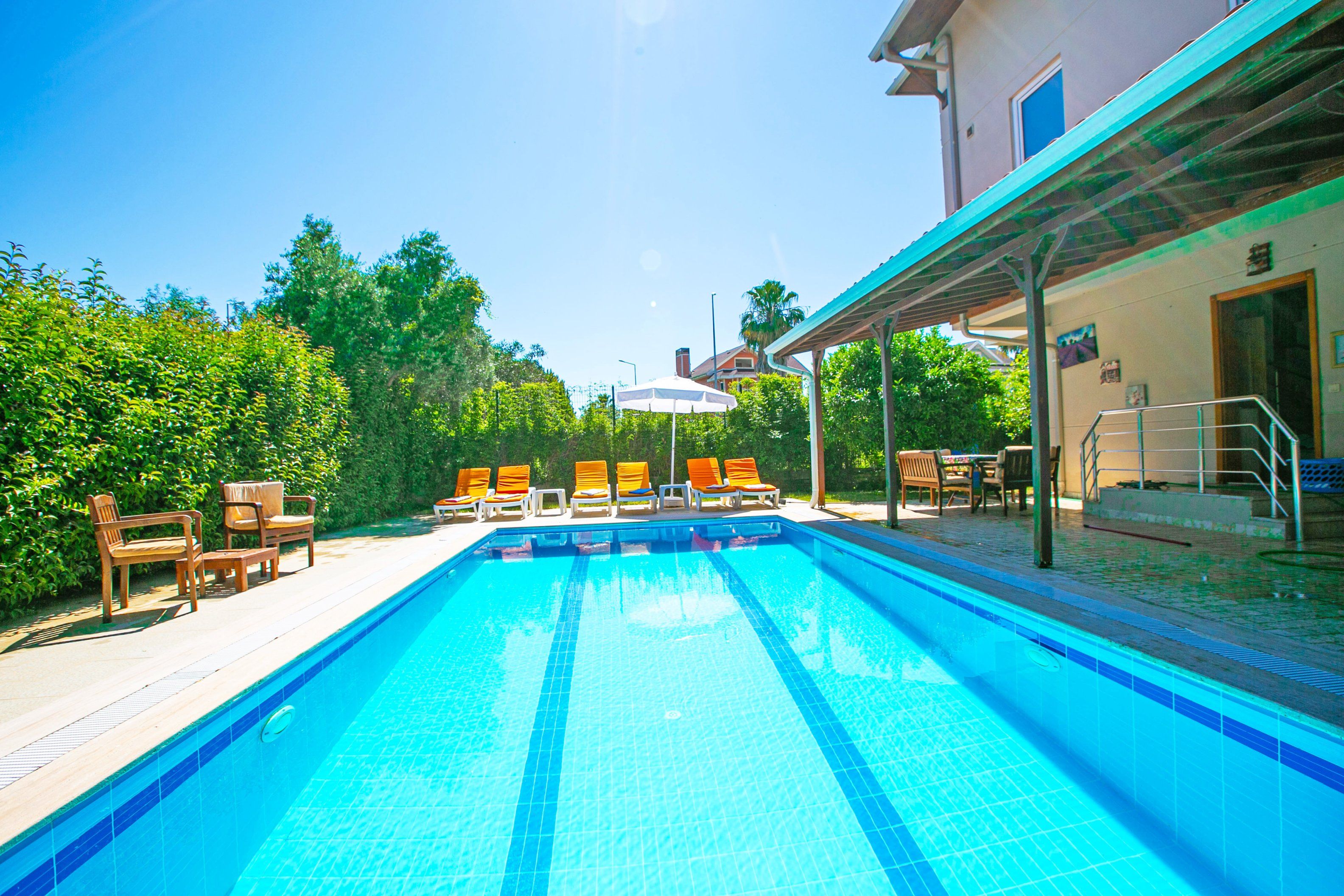 Piscina com espreguiçadeiras e área coberta.