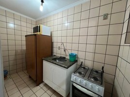 Cozinha compacta com geladeira, pia, fogão a gás e armários.