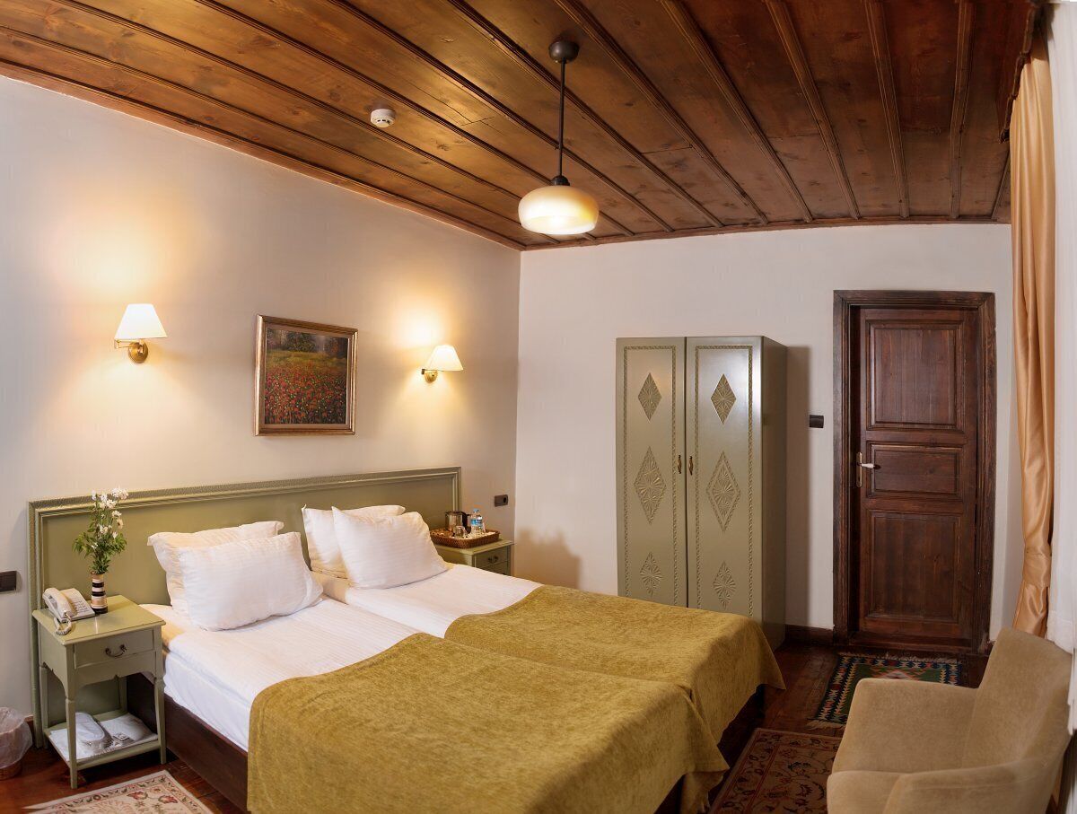Quarto de hotel com cama de casal, duas mesas de cabeceira, um guarda-roupa e uma cadeira.