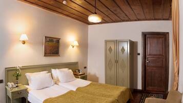 Quarto de hotel com cama de casal, duas mesas de cabeceira, um guarda-roupa e uma cadeira.