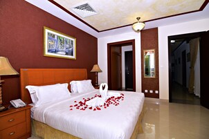 Quarto de hotel com uma cama grande, telefone de mesa e um quadro emoldurado na parede.