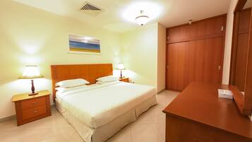 Quarto de hotel com cama, duas mesas de cabeceira com luminárias, um guarda-roupa de madeira e um quadro na parede.