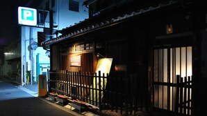 Um edifício tradicional em estilo japonês com uma placa indicando 'DEER Chest House' e uma placa de estacionamento.