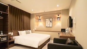 Quarto de hotel moderno com uma cama grande, uma mesa com telefone e uma televisão.
