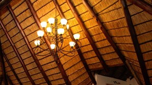 Um quarto de sótão acolhedor com teto de colmo alto, um candelabro e sofás com padrão xadrez.