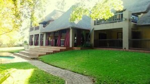 Uma casa de dois andares com varanda coberta e piscina.