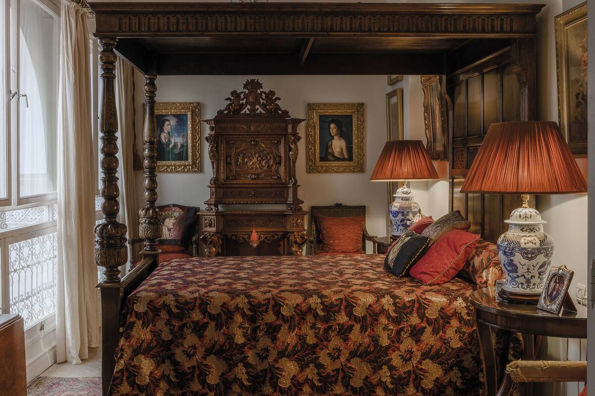 Quarto tradicional com cama grande, móveis de madeira ornamentados e decoração clássica.