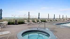 Área da piscina com espreguiçadeiras e banheira de hidromassagem, com vista para a praia.