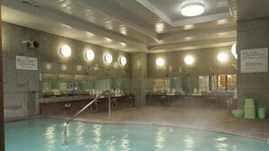 Uma grande piscina coberta com várias áreas de chuveiro e espelhos.