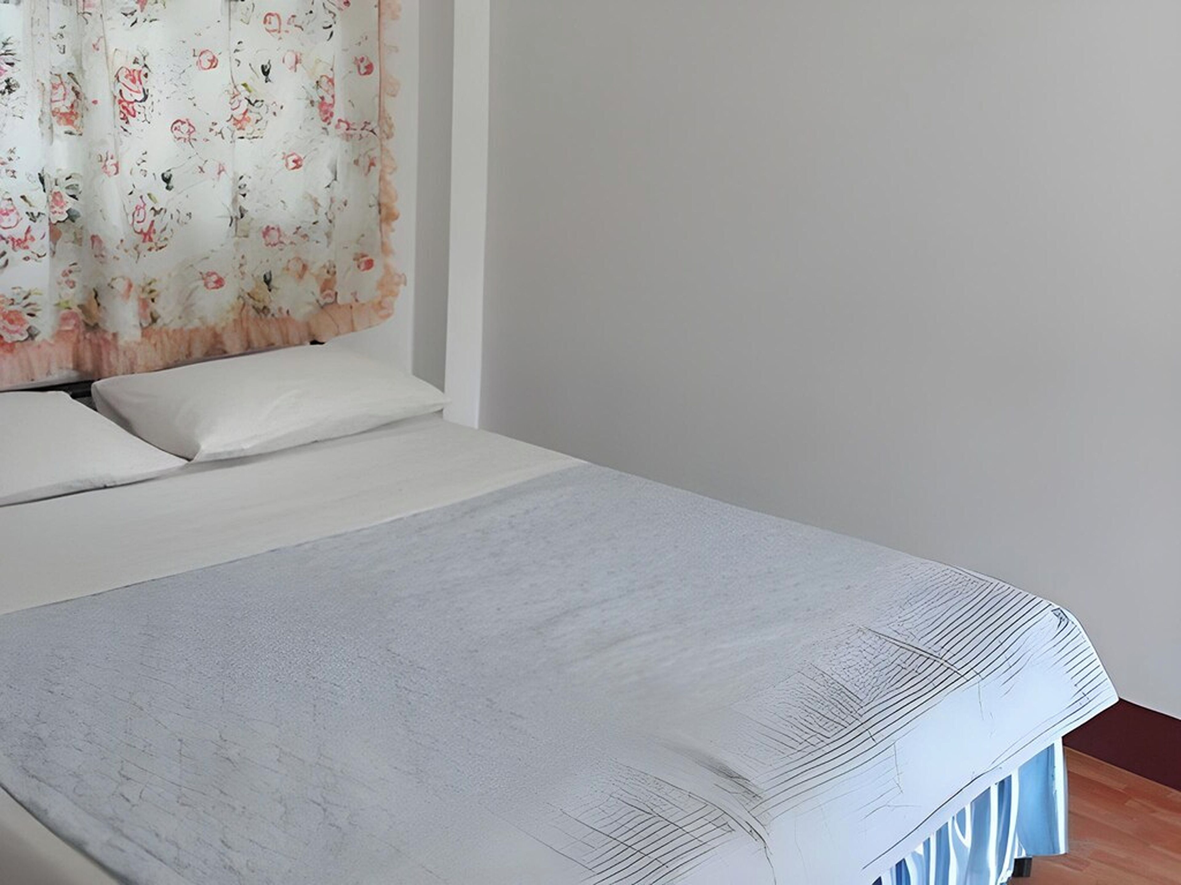 Uma cama com lençol branco e cortina estampada.