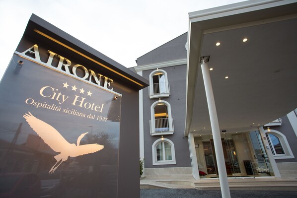 Exterior do Hotel AIRONTE City, com placa mostrando uma silhueta de pássaro e o nome do hotel.