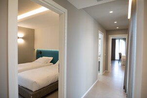 Quarto de hotel com duas camas, um banheiro e um corredor que leva a uma área de refeições.
