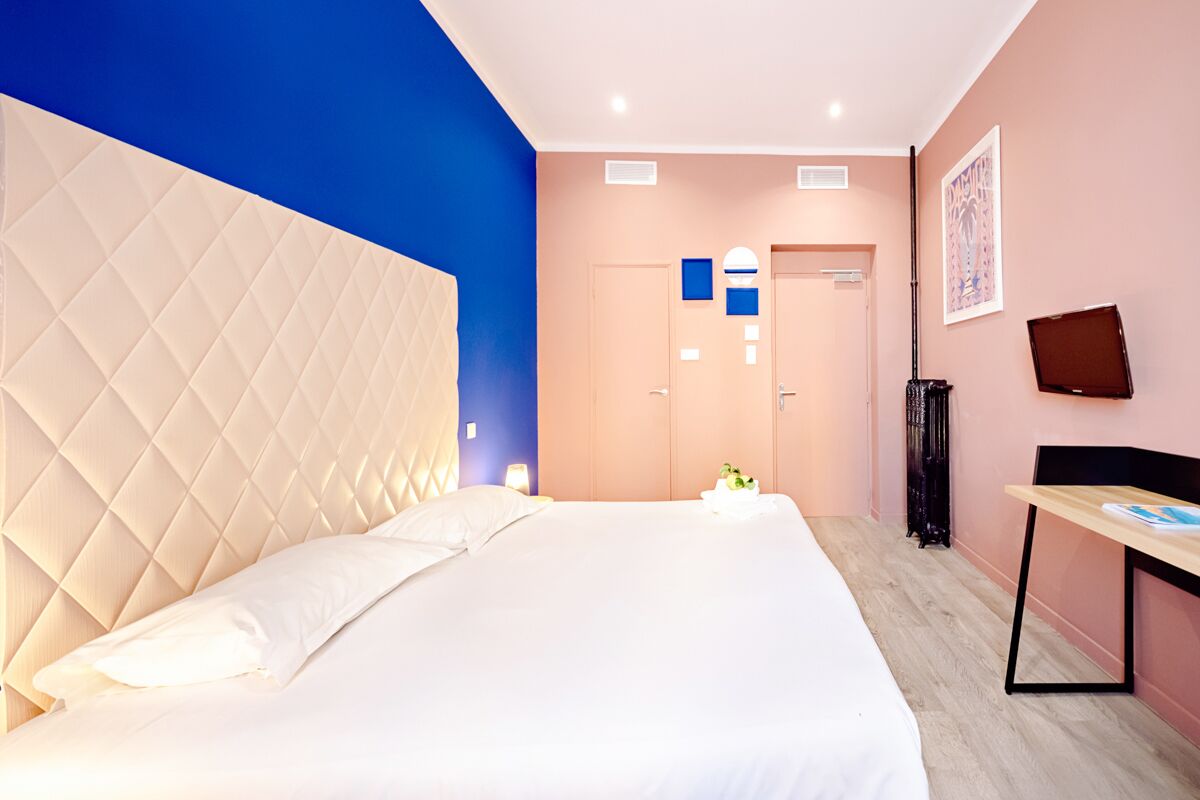 Quarto de hotel moderno com uma cama grande, uma escrivaninha e uma porta.