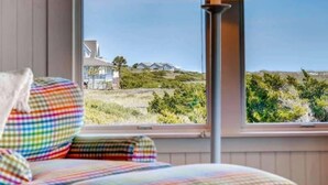 Quarto com uma janela ampla que oferece vista para casas e áreas verdes.