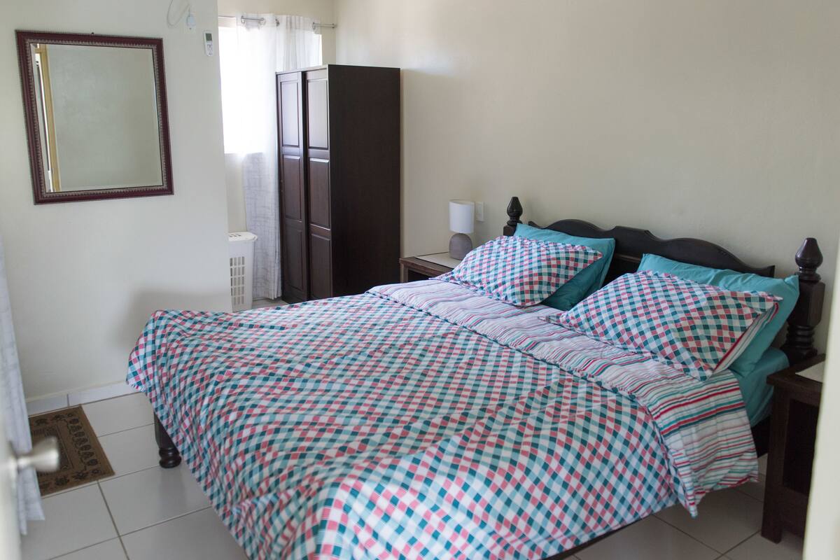 Quarto com cama, mesa de cabeceira, cômoda e espelho.