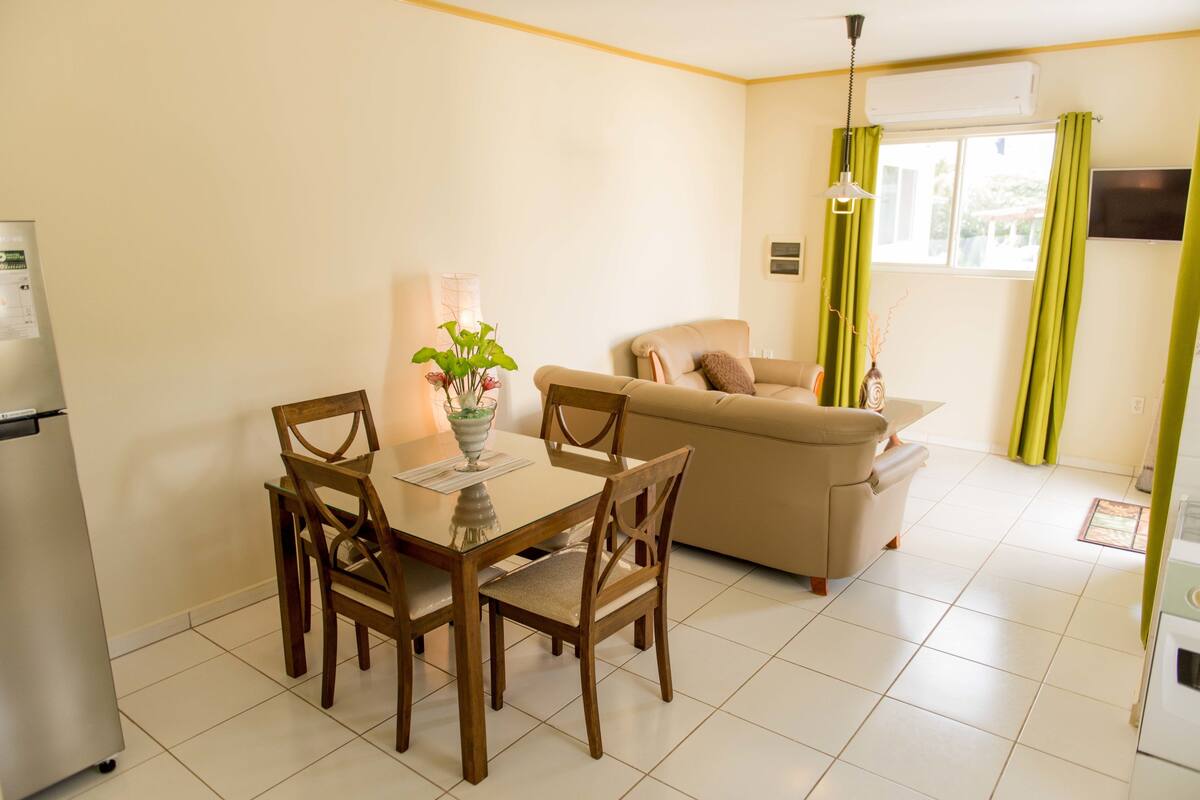 Espaço compacto com área de jantar, sofá e televisão.