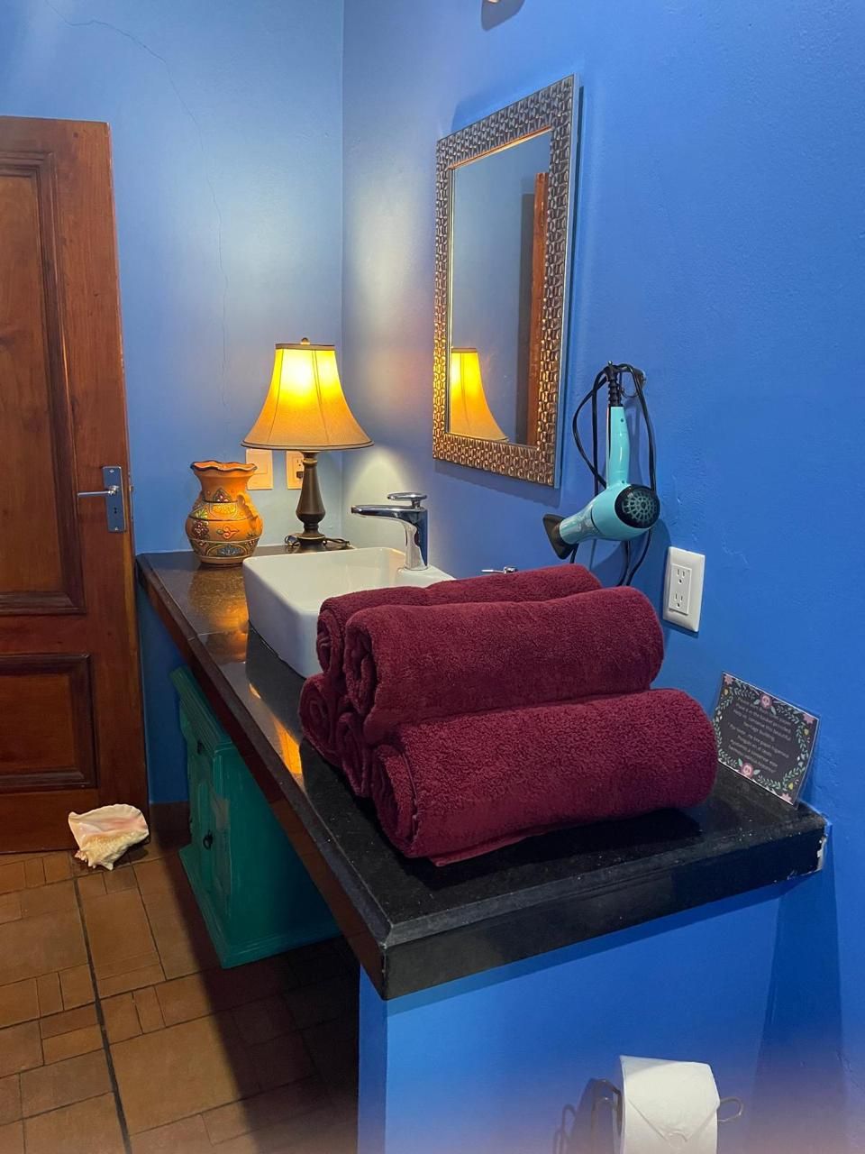 Uma casa de banho com lavatório, espelho, porta-toalhas e secador de cabelo.