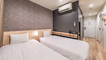 Quarto de hotel com duas camas, escrivaninha embutida, ar condicionado e porta com placa de número.