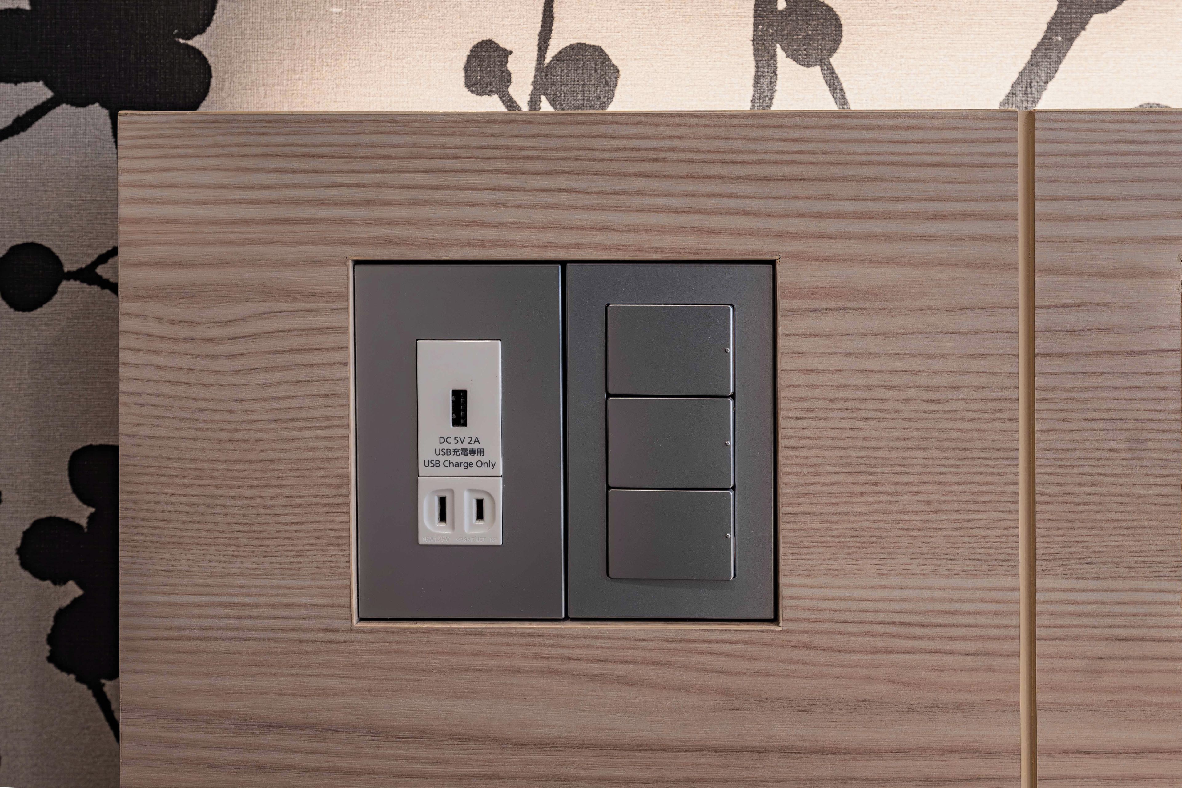 Tomada elétrica na parede com porta USB para carregamento, uma tomada padrão e um interruptor.