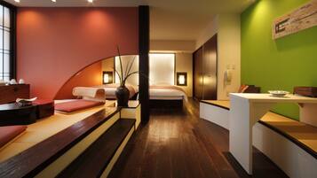 Quarto de hotel moderno com área de estar curvada, uma cama, uma mesa de trabalho e uma parede verde de destaque.