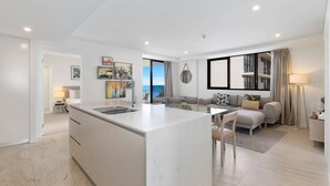 Uma sala de estar moderna com uma ilha grande, um conjunto de sofá e vista para o mar.