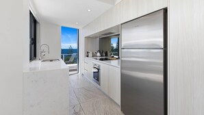 Uma cozinha moderna com geladeira de aço inoxidável, forno embutido e uma grande janela com vista panorâmica.