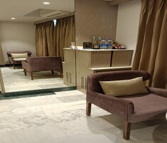 Quarto de hotel com área de estar, incluindo dois sofás e um armário com artigos de higiene pessoal.
