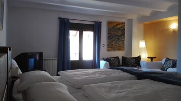 Quarto de hotel com duas camas, uma televisão, um quadro na parede e um abajur.