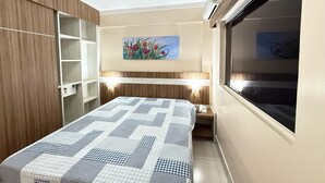 Quarto com cama, pintura de flores, guarda-roupa e janela.