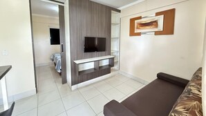 Uma sala de estar moderna com televisão de tela plana, sofá e área de jantar.