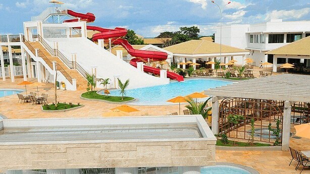 Um parque aquático com várias escorregas, piscina e áreas de estar ao ar livre.