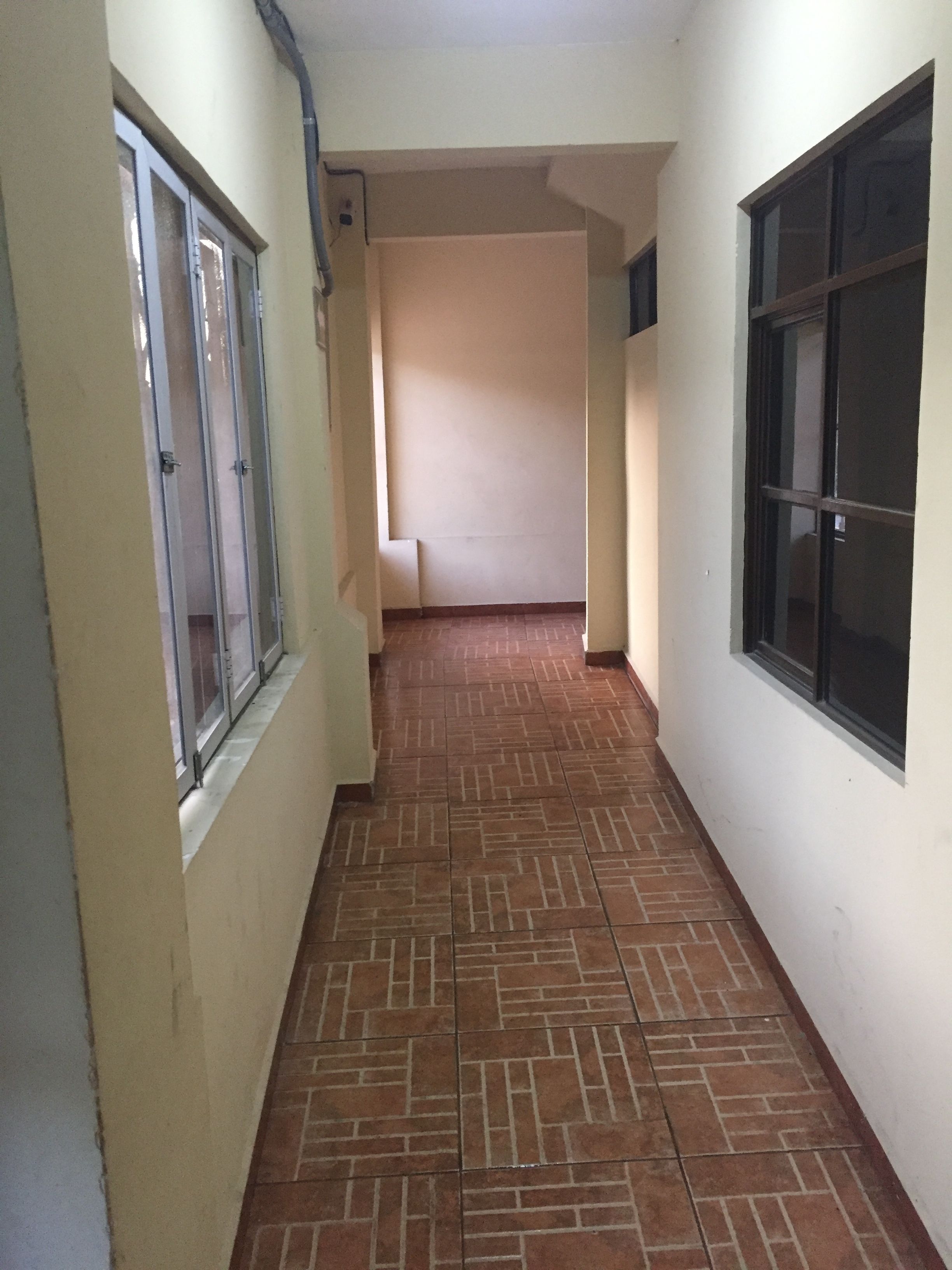 Um corredor estreito com piso de azulejos e paredes brancas.