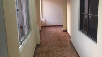 Um corredor estreito com piso de azulejos e paredes brancas.