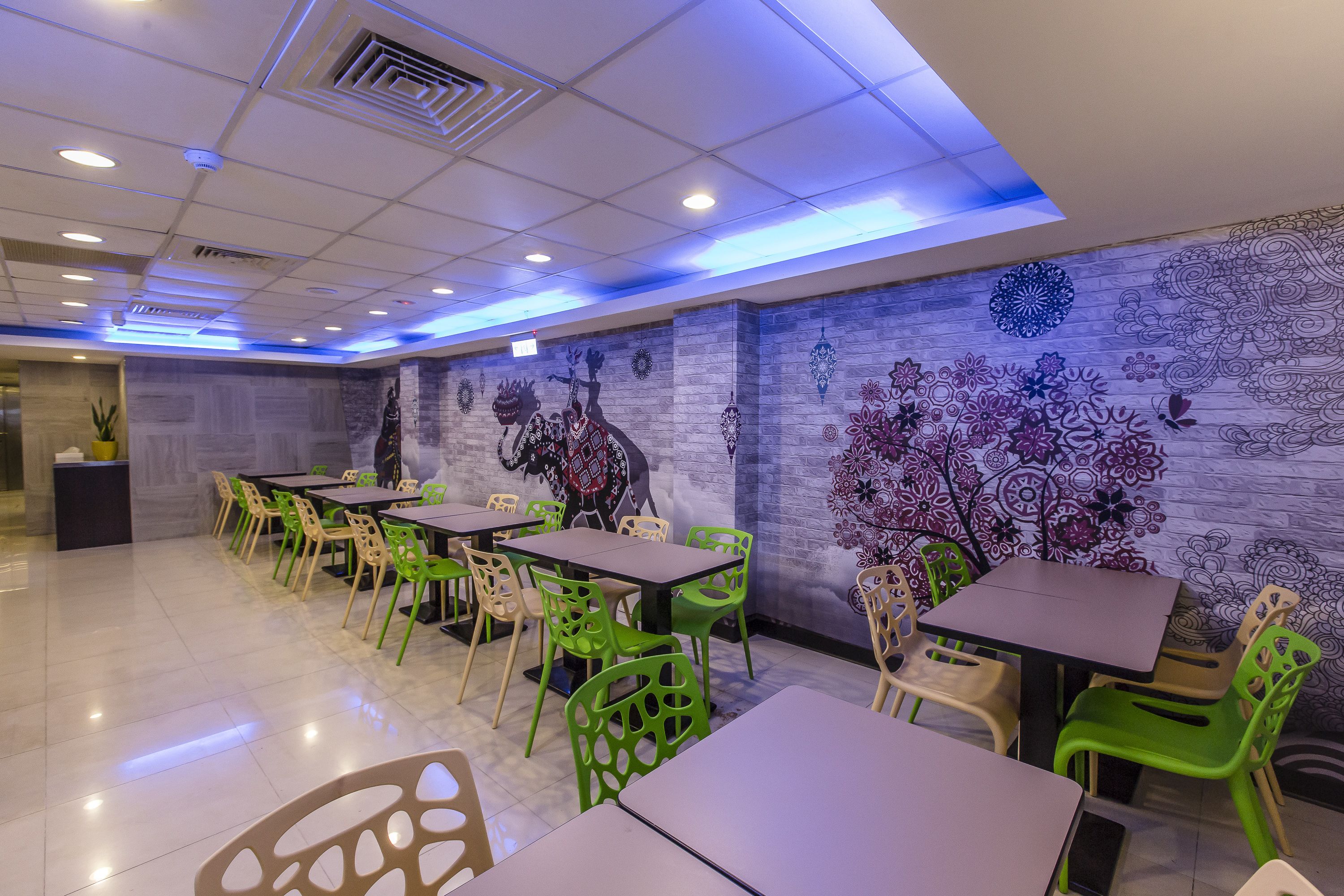 Um restaurante com uma mesa comprida e cadeiras, parede estampada e teto com iluminação embutida.