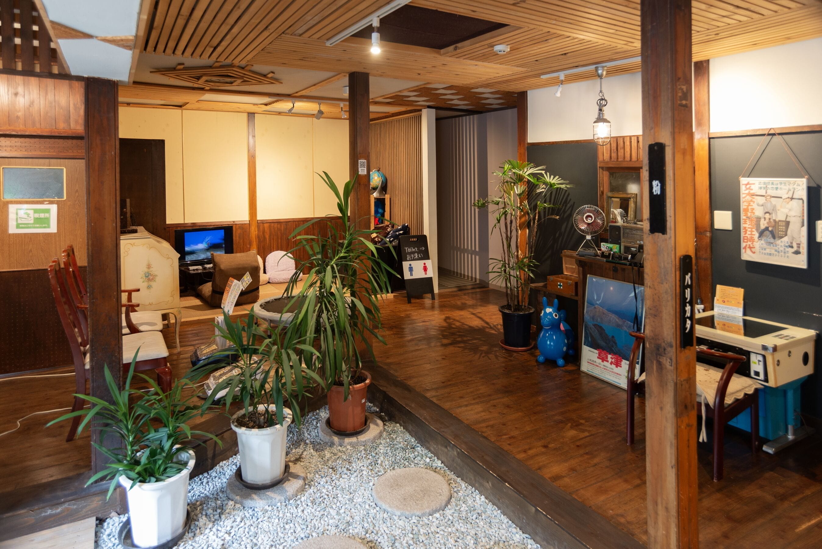 Um quarto tradicional em estilo japonês, com tatames, uma televisão e diversas plantas.